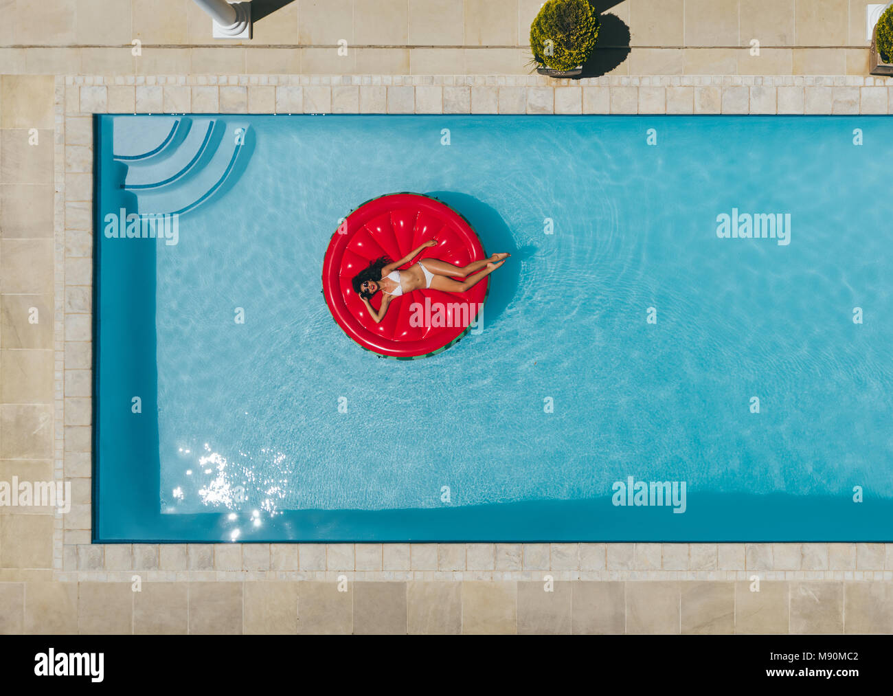 Woman relaxing on big red floating mattress in the pool water on hot ...