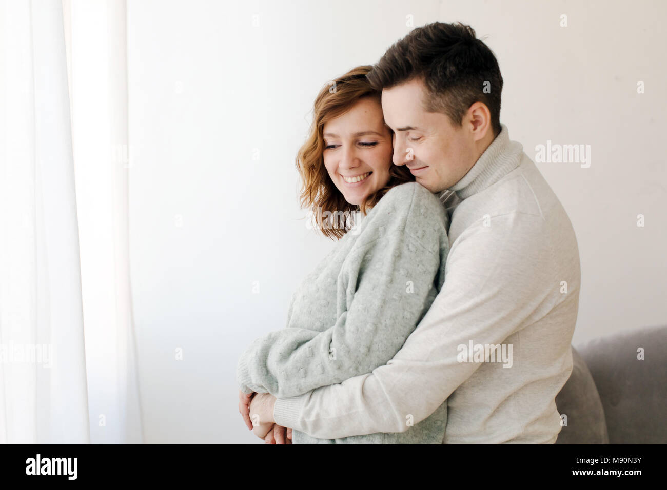 Cute couple hugging and smiling in their home Stock Photo - Alamy