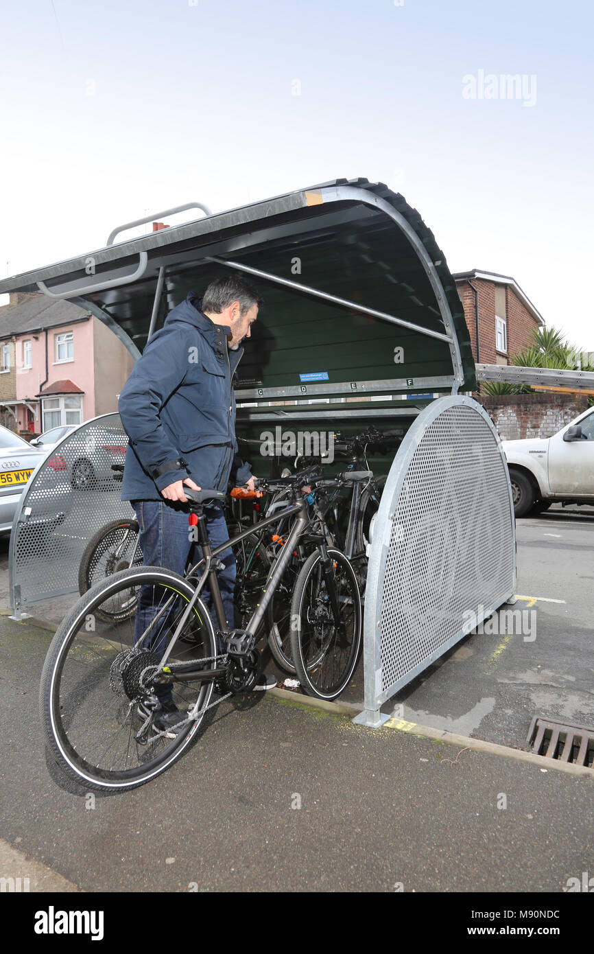 A cyclist places his bike into a secure on-street bicycle store ...