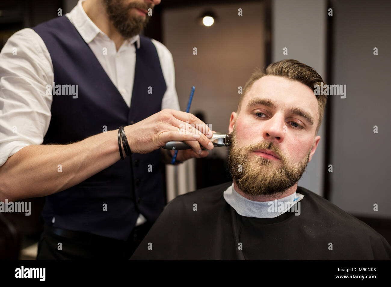 Portrait of barber trimming young man Stock Photo - Alamy
