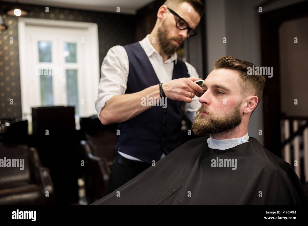 Profile portrait of young man having haircut in hair salon Stock Photo ...