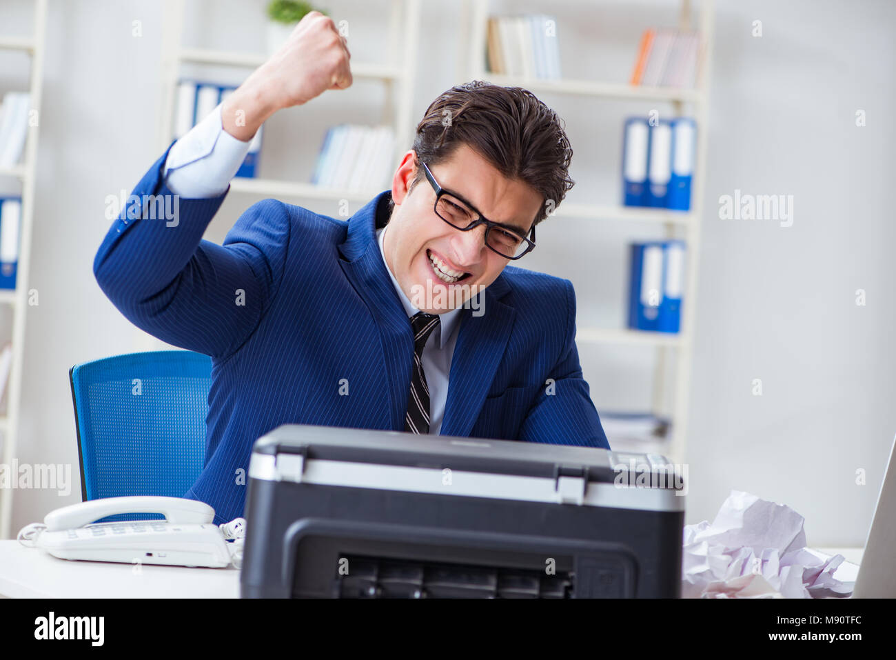 Businessman angry at copying machine jamming papers Stock Photo - Alamy