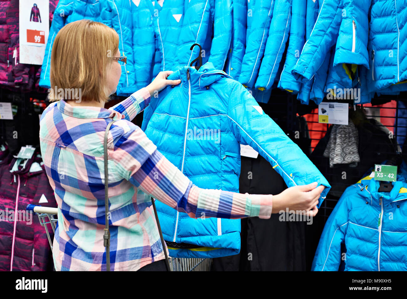 Woman chooses a winter jacket in the store Stock Photo - Alamy