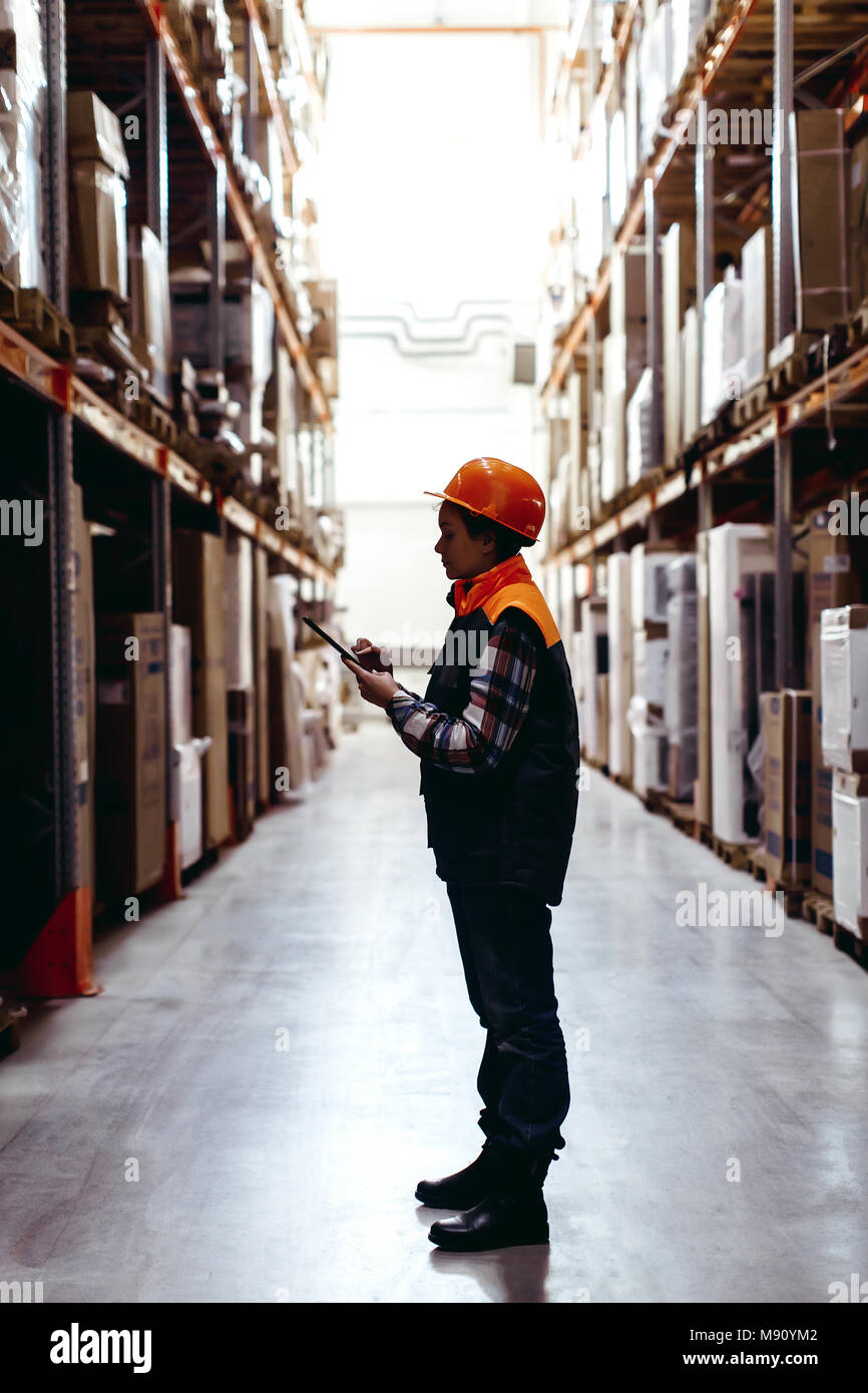 Side view of woman worker standing with papers in warehouse Stock Photo ...