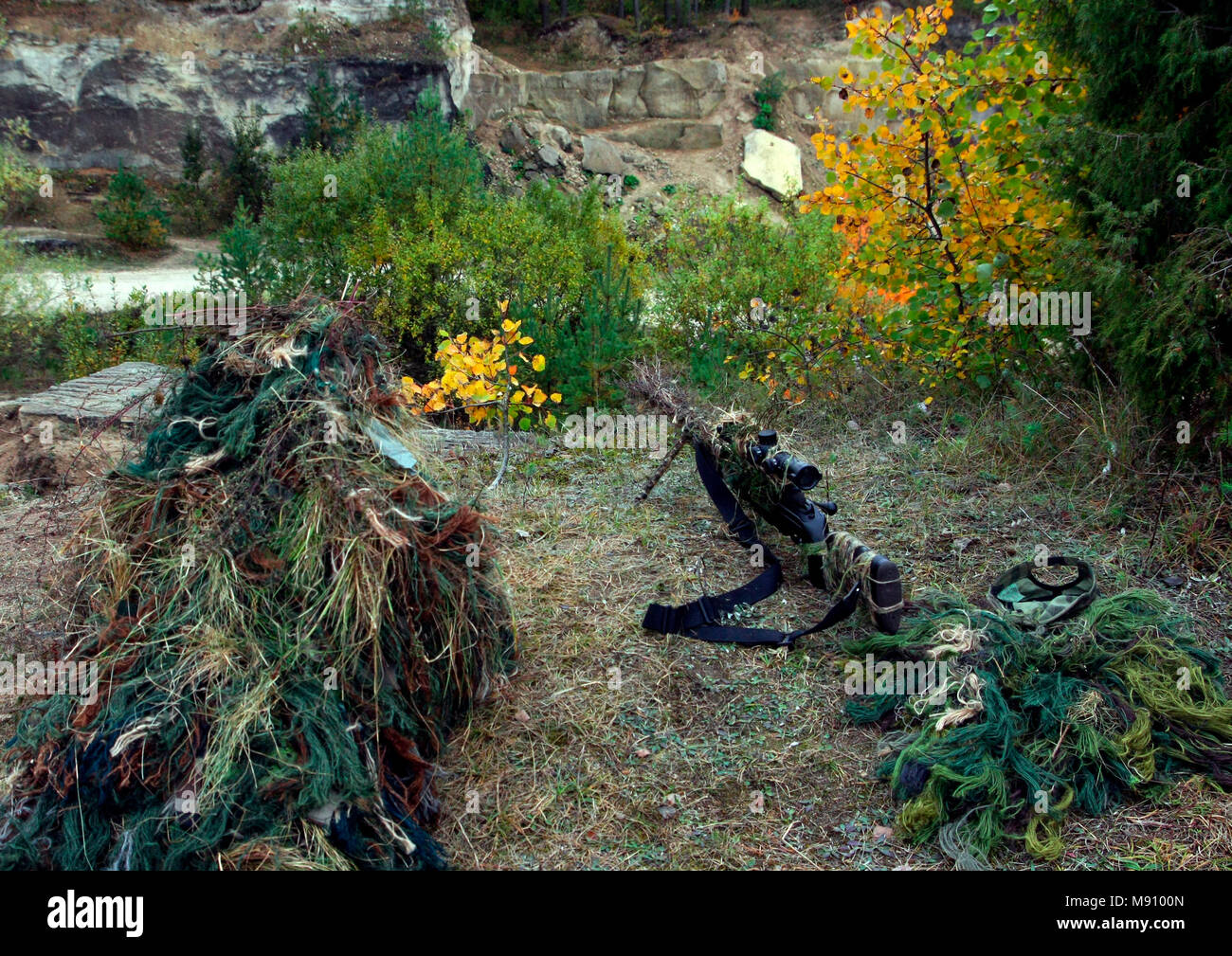 Camouflage Hunter or soldier hiding in bushes in camouflage autumn ...