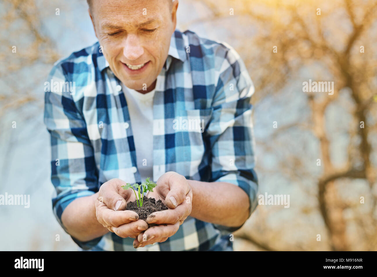 Positive smiling man holding a handful of soil Stock Photo - Alamy
