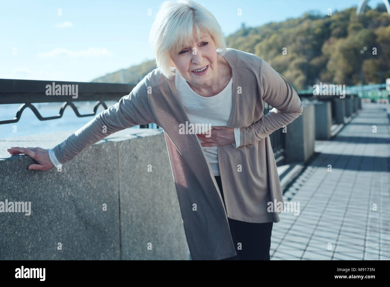 Retired lady doubling over due to severe pain Stock Photo - Alamy
