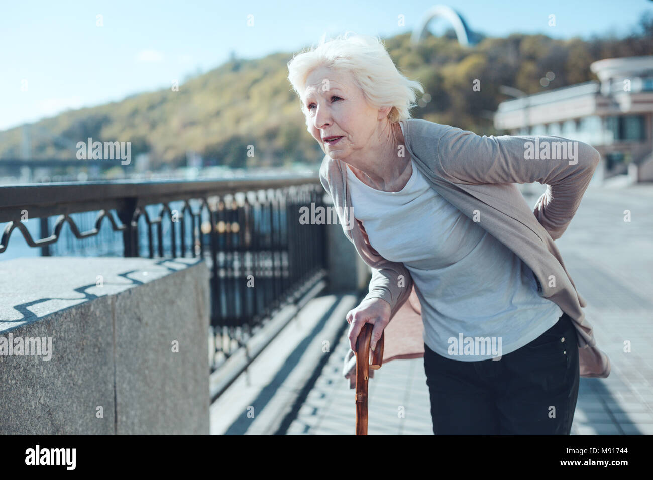 Physically exhausted woman doubling over with back pain Stock Photo - Alamy