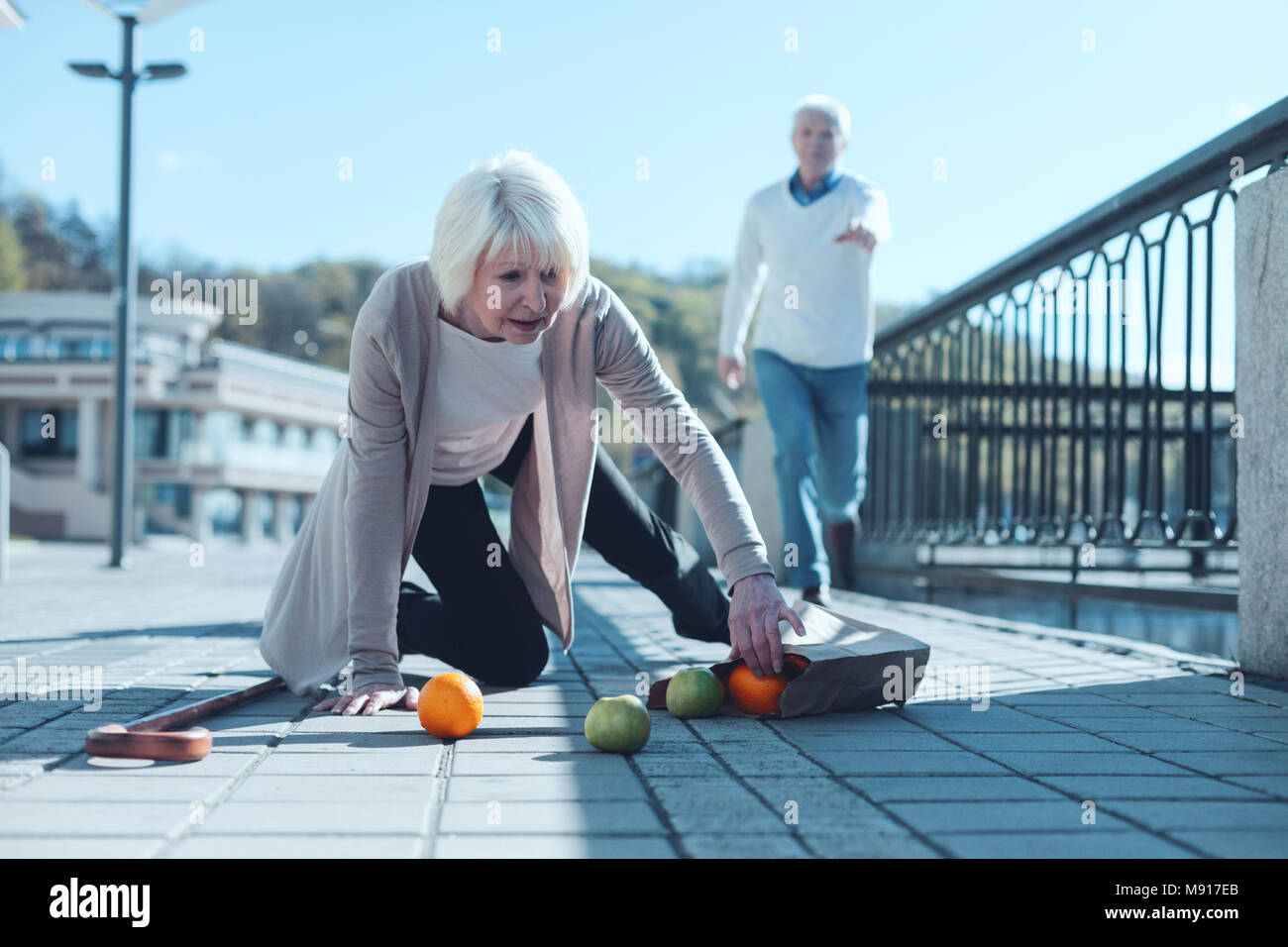 Scared woman dropping groceries while falling to ground Stock Photo - Alamy