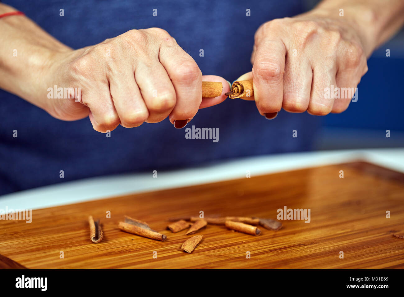 Man breaking a cinnamon stick over a wooden board Stock Photo - Alamy