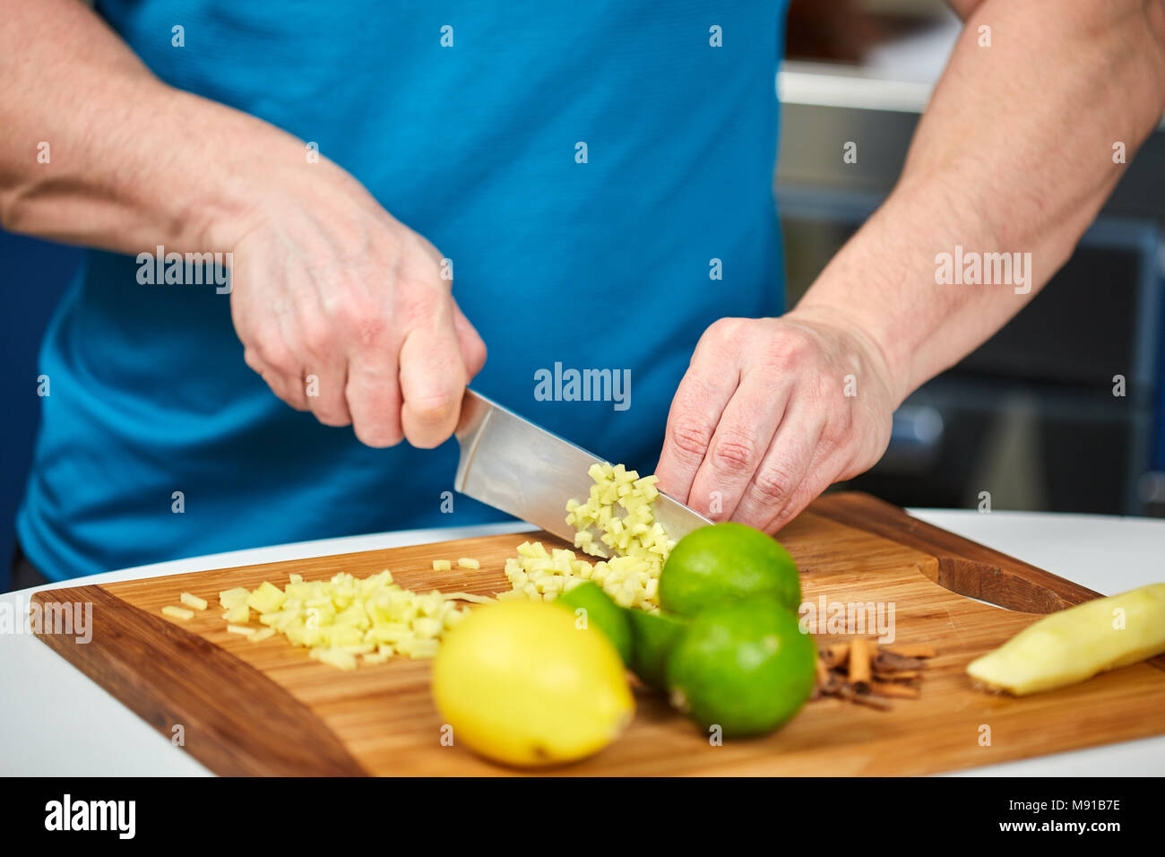 Man chopping fresh ginger on a wooden board for a recipe Stock Photo ...