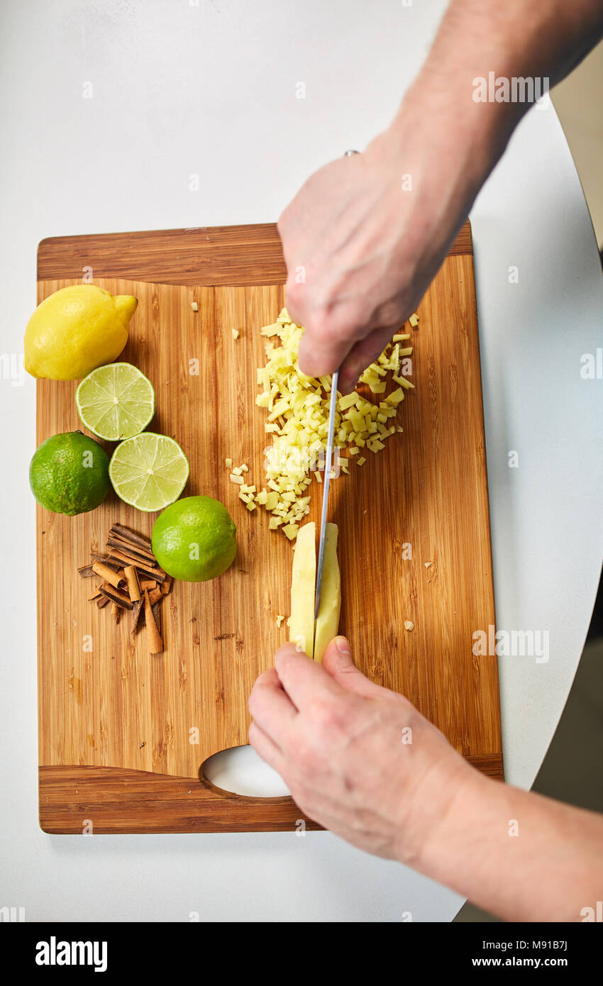 Man chopping fresh ginger on a wooden board for a recipe Stock Photo ...