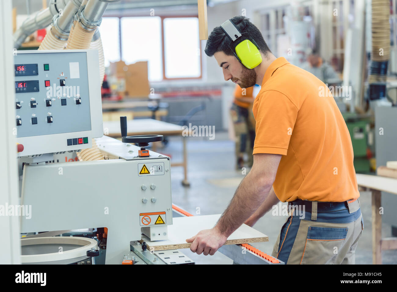 Carpenter working in furniture factory on machine Stock Photo - Alamy