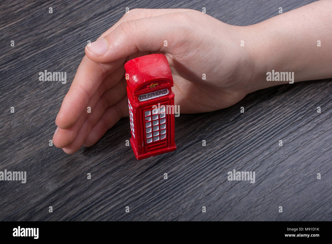 Hand holding a phone booth on a brown background Stock Photo - Alamy