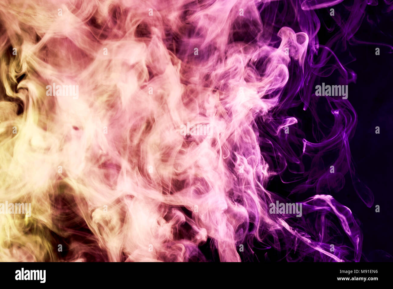 Dense multicolored smoke of yellow, pink and red colors on a black ...