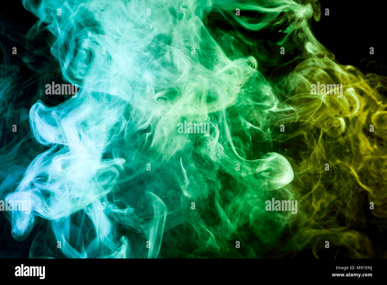 Thick colorful smoke of yellow, green and blue on a black isolated ...
