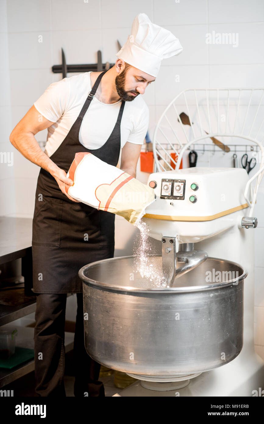 Baker filling flour into the kneader Stock Photo - Alamy