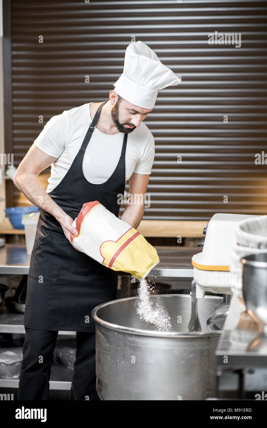 Baker filling flour into the kneader Stock Photo - Alamy