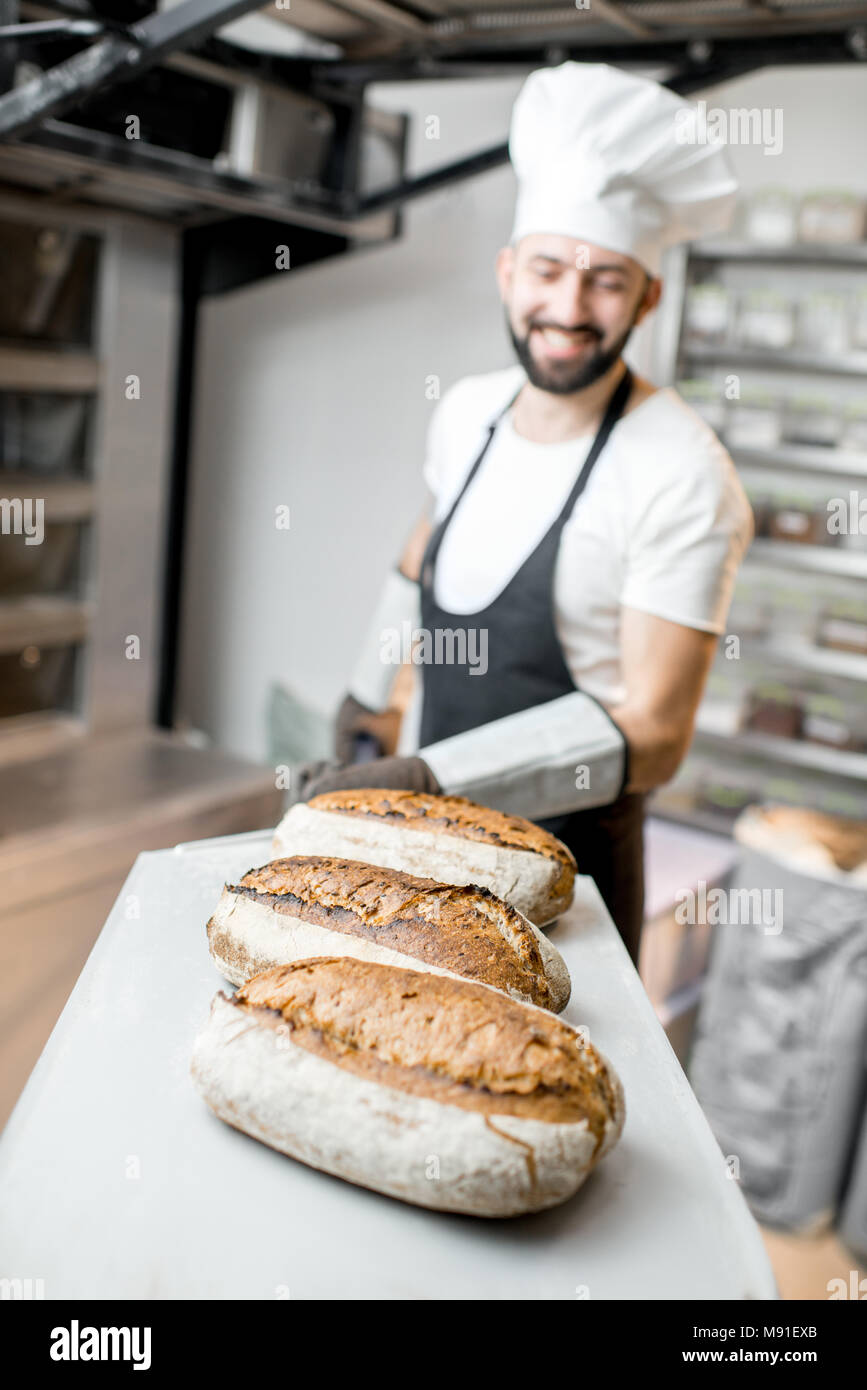 Baker with baked breads at the bakery Stock Photo - Alamy