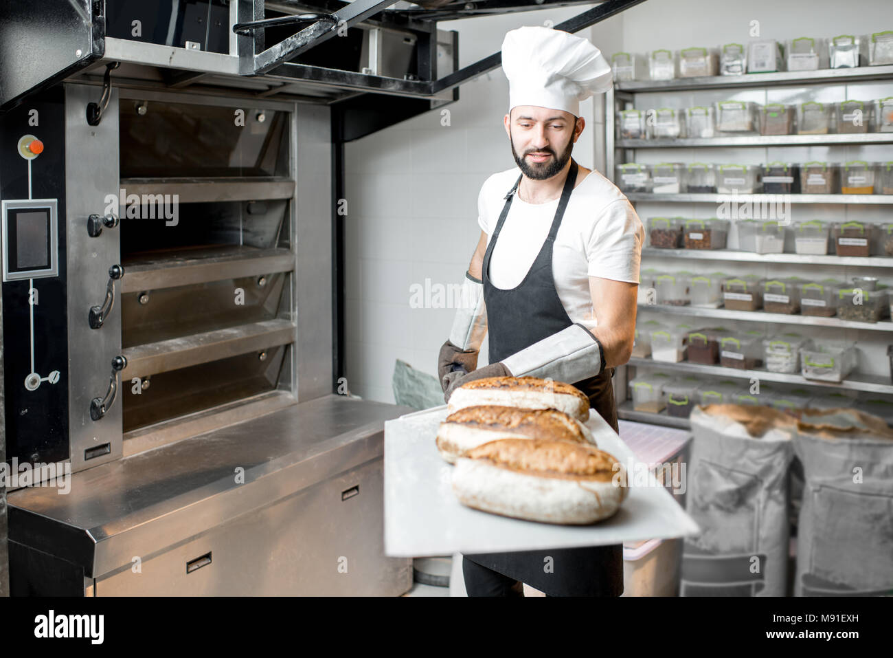 Baker with baked breads at the bakery Stock Photo - Alamy