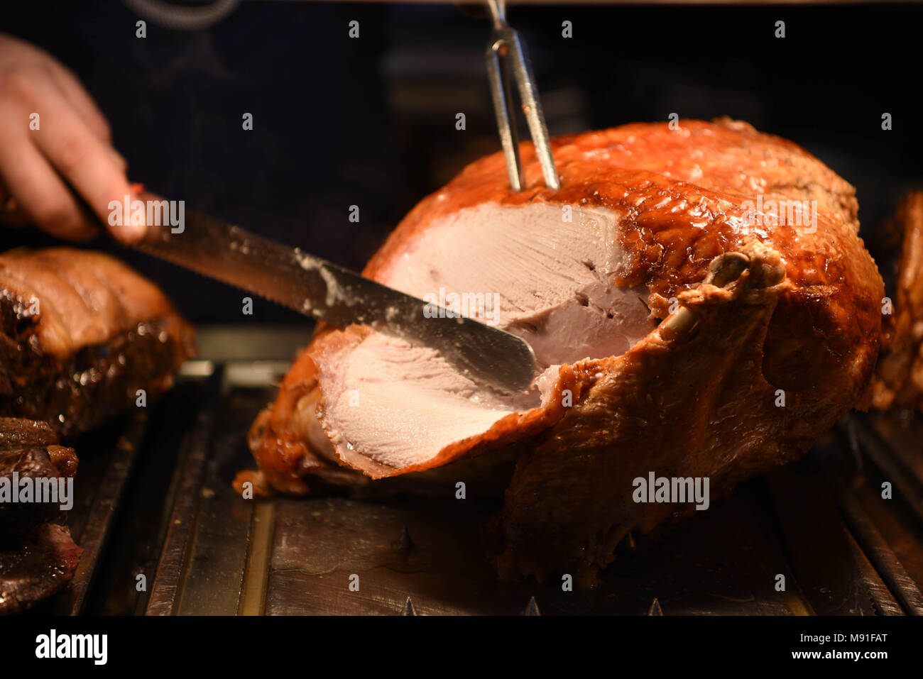 succulent whole roast turkey being carved with knife fork and chef hand ...