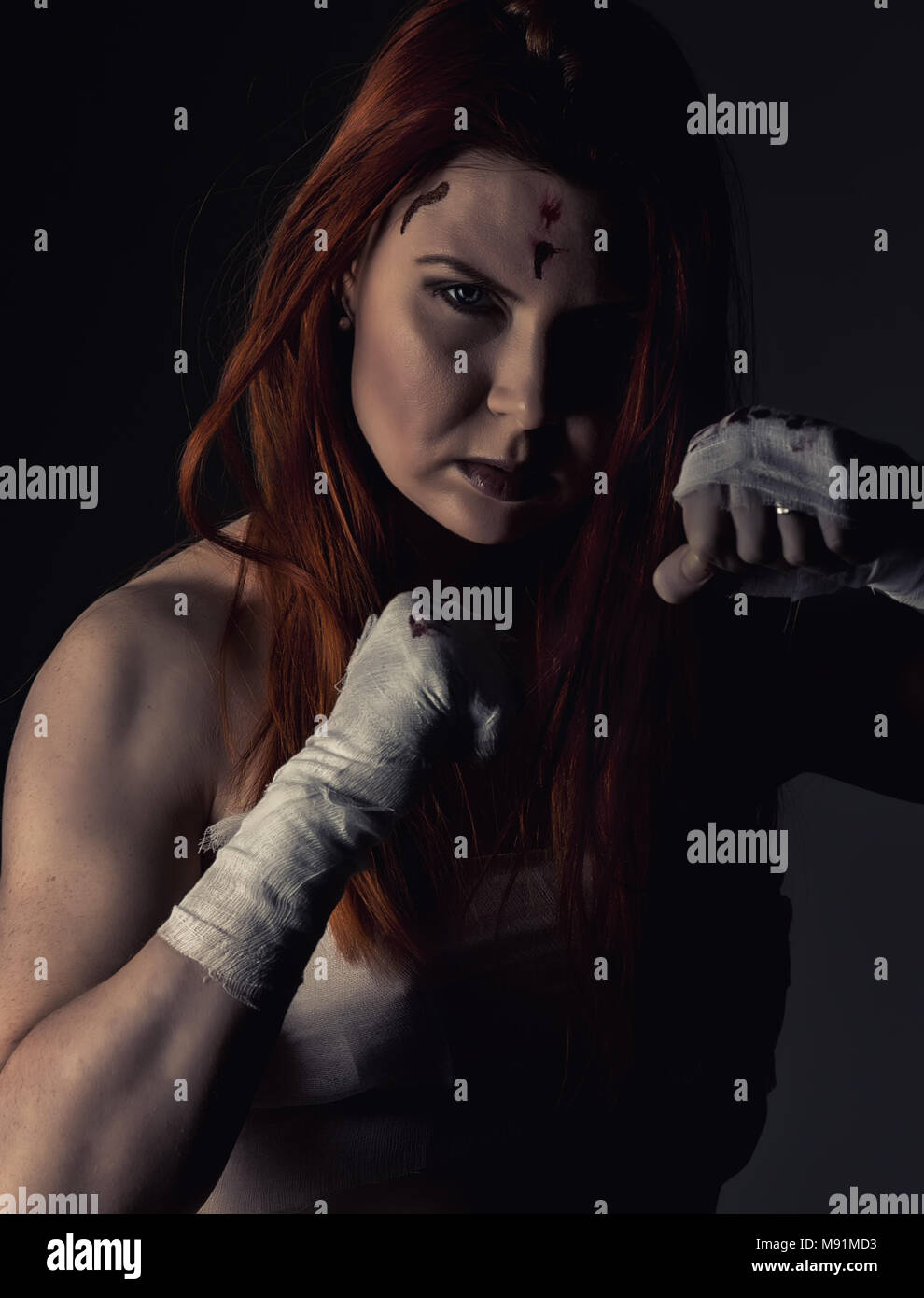 Beautiful young female fighter after the fight on a dark background ...
