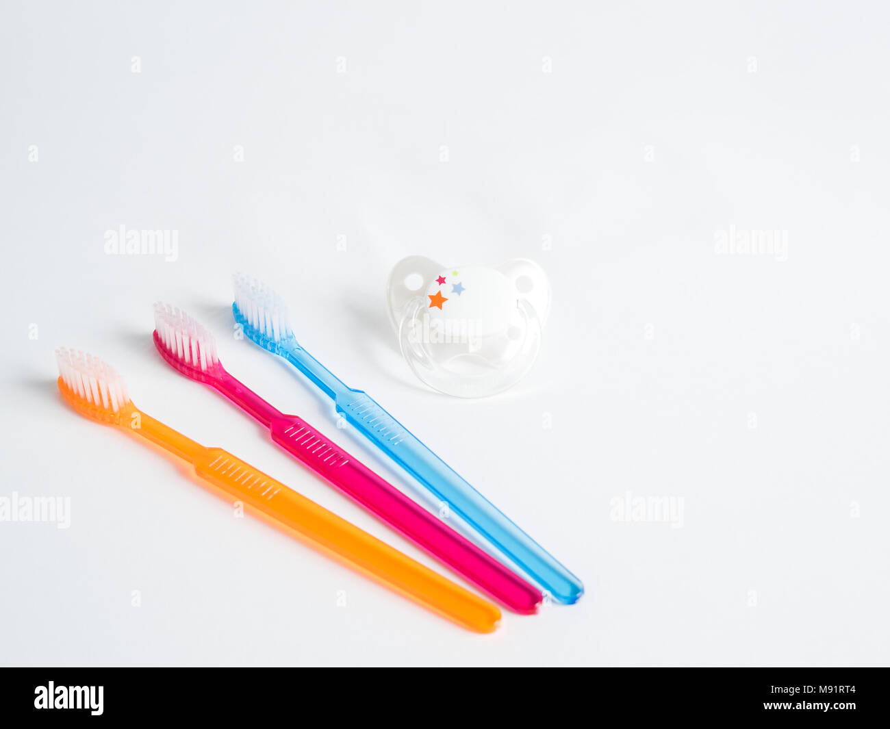 Three toothbrushes in a glass with pacifier on a white background Stock ...