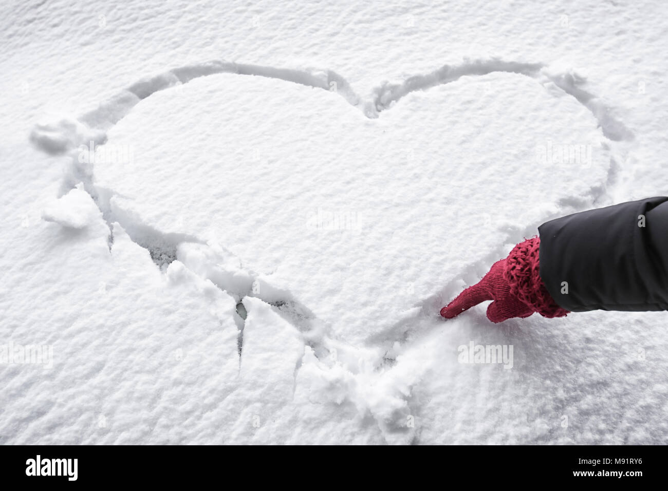 Woman drawing heart shape in the snow Stock Photo - Alamy