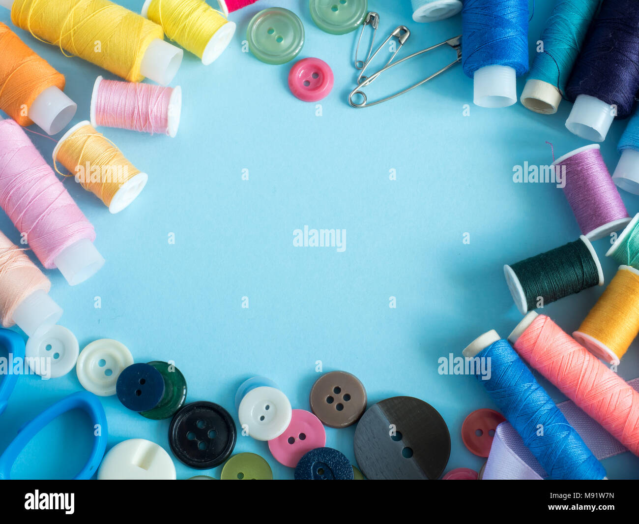 Multicolored sewing threads and buttons on blue background with copy ...