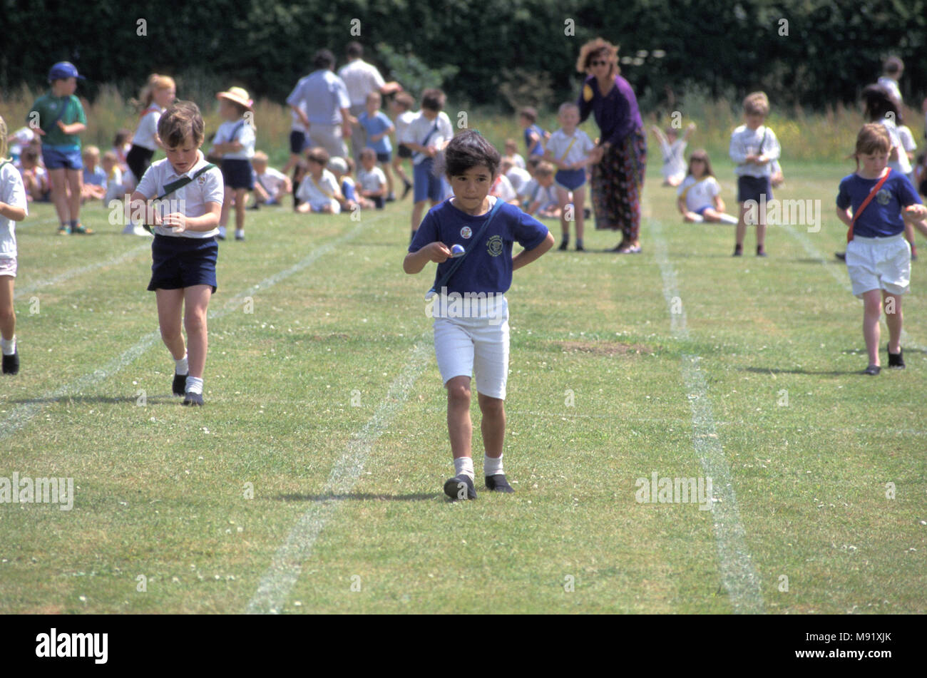 primary school chldren competing in egg and spoon race during sports ...