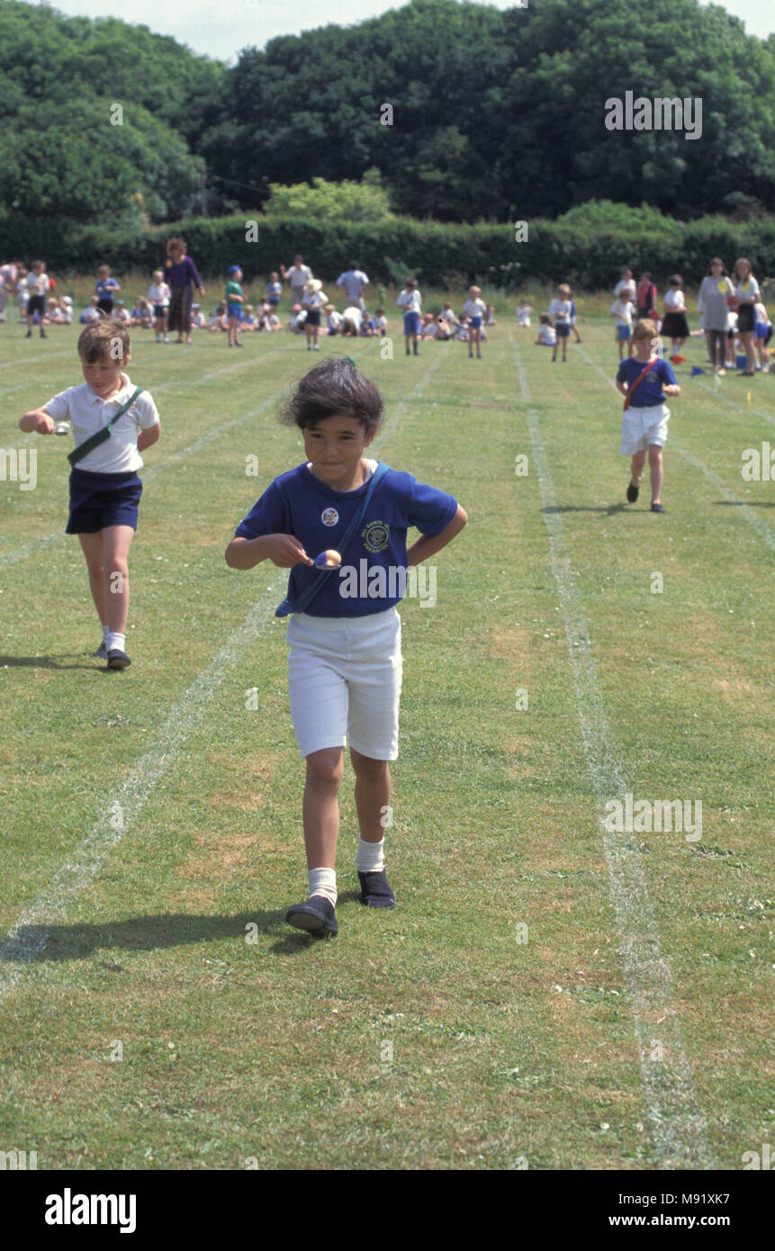 primary school chldren competing in egg and spoon race during sports ...