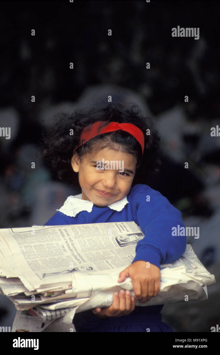 multicultural little girl in paper standing in paper recycling plant ...