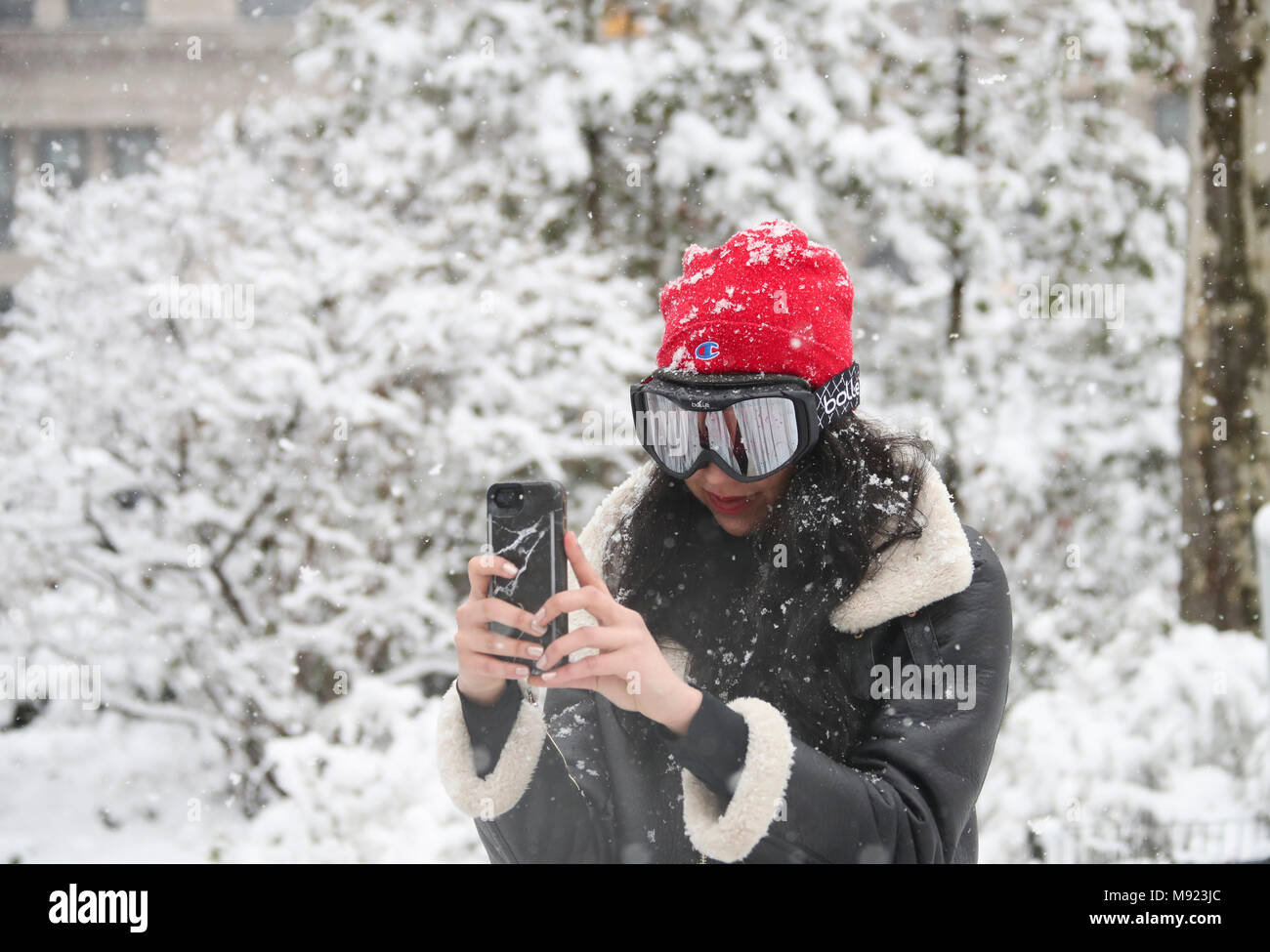 New York, USA. 21st Mar, 2018. A woman takes photos in snow at Madison ...
