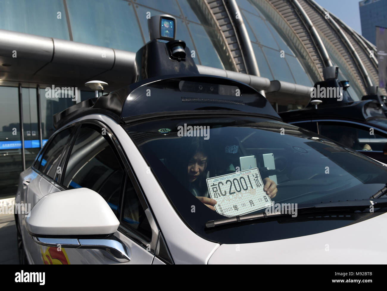 Beijing, China. 22nd Mar, 2018. A staff member puts a temporary license ...
