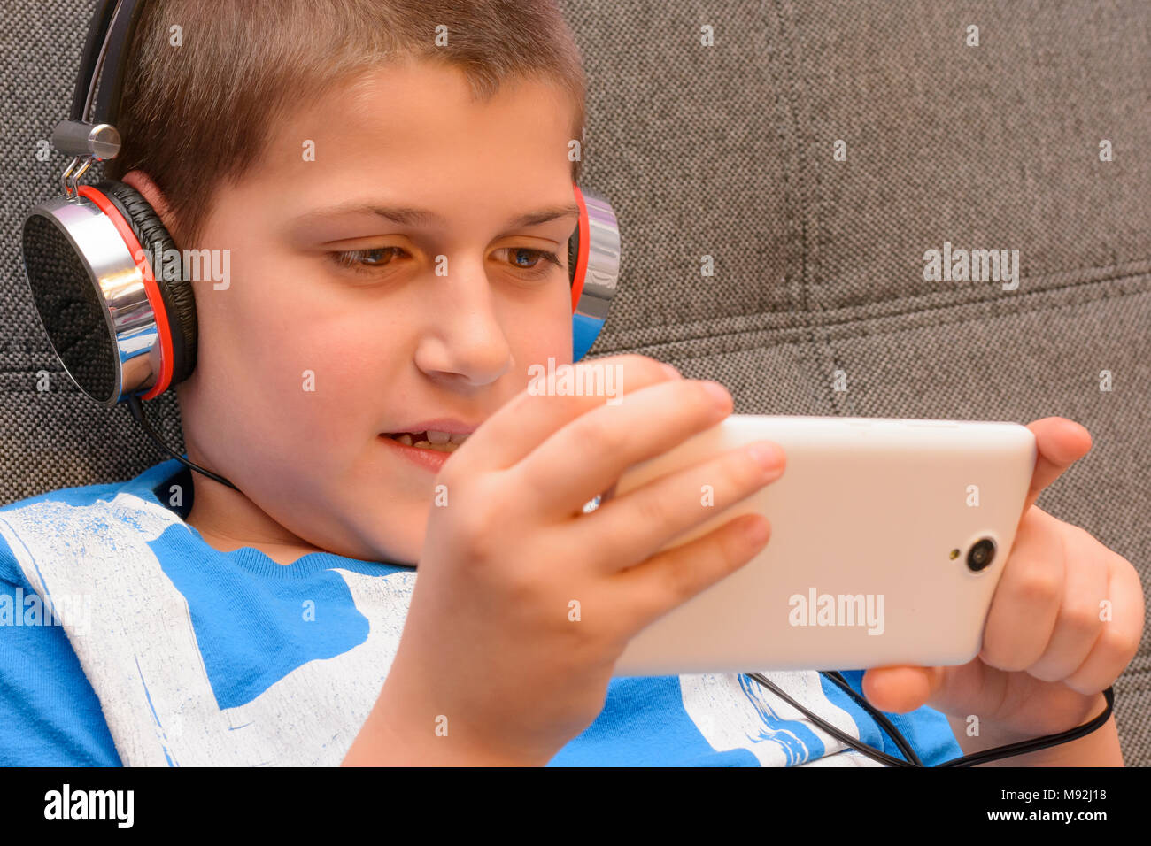 Boy with headphones and mobile phone in hand. A boy listening to music ...