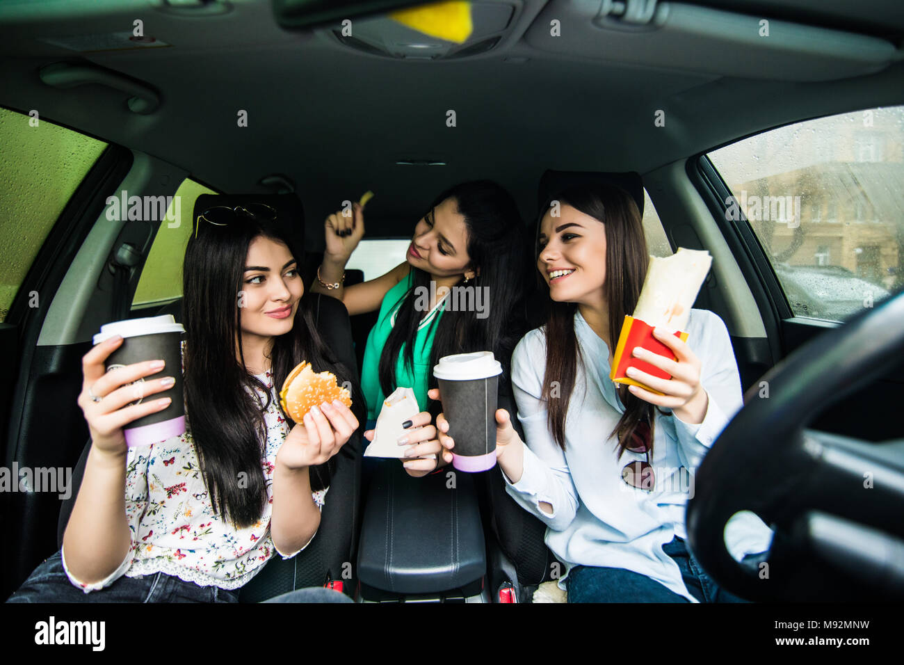 Beautiful stylish girls are making selfie, looking at camera, eating ...