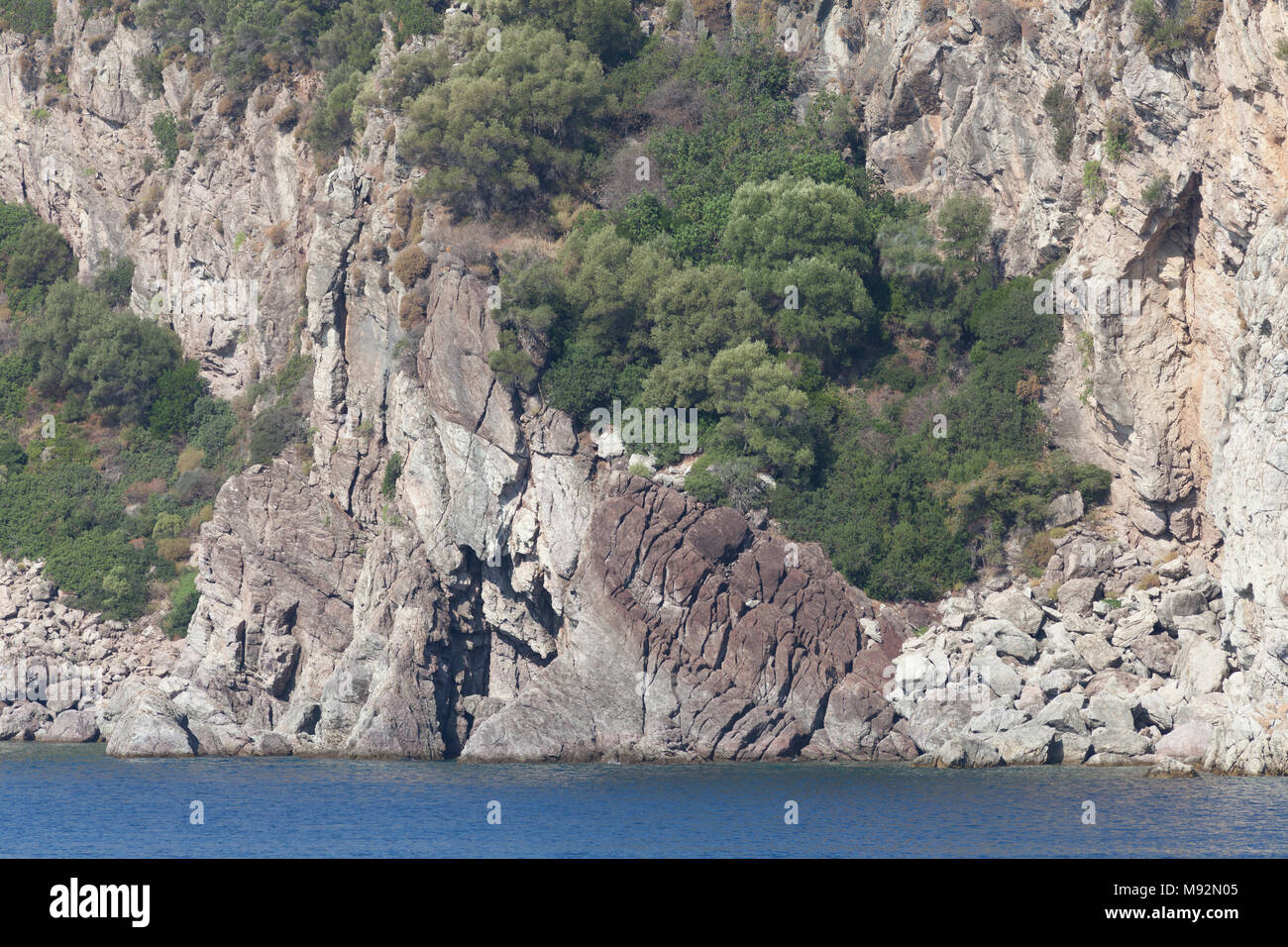 Rocky cliff overgrown with bushes on the Mediterranean Sea near ...