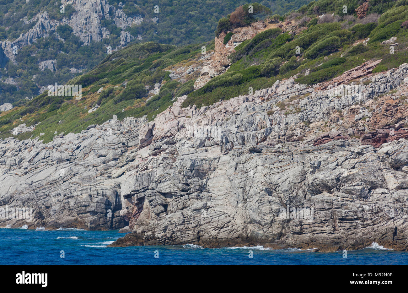 Rocky cliff overgrown with bushes on the Mediterranean Sea near ...