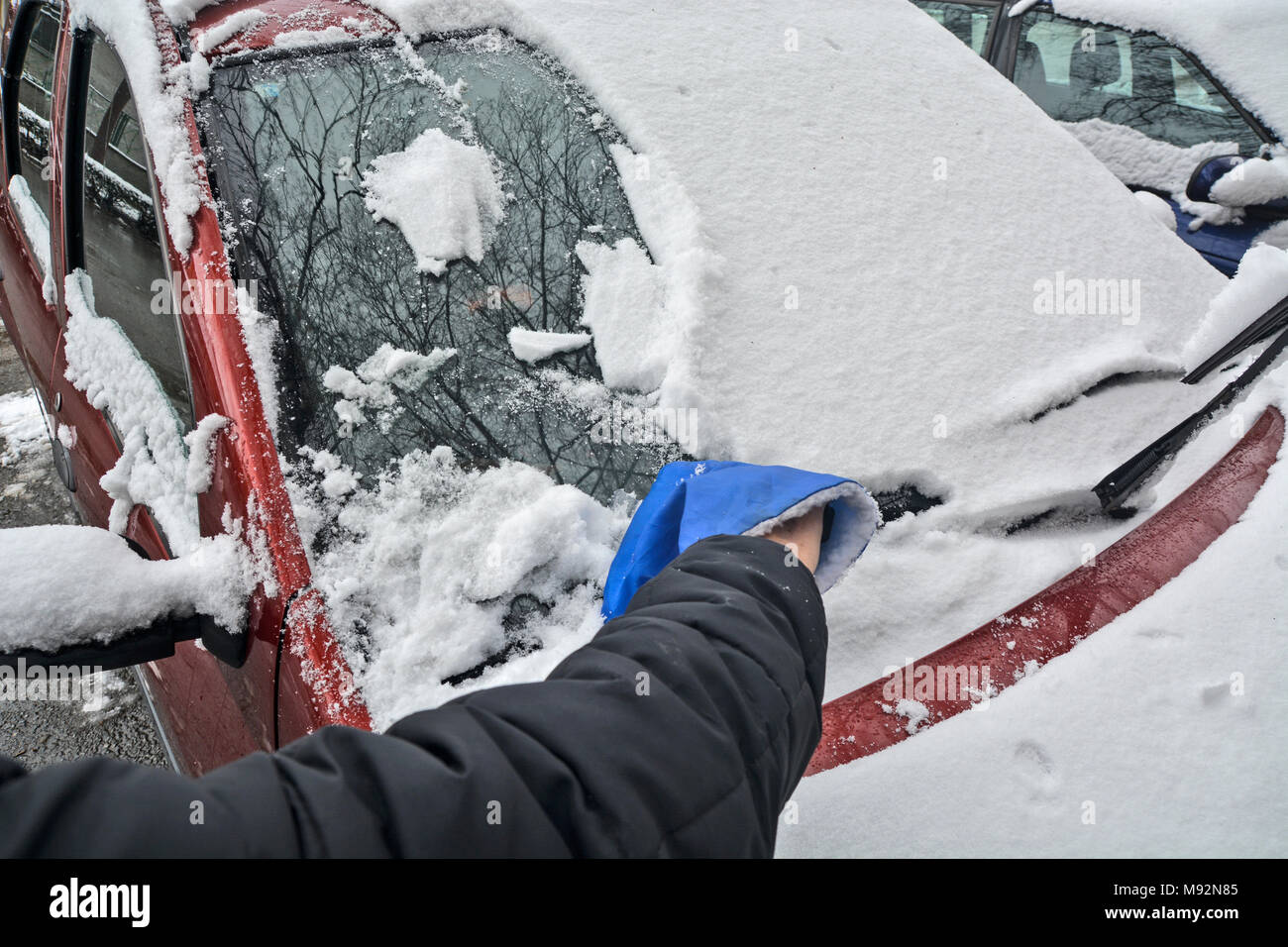 Driver cleaning snow from windshield of car using scraper Stock Photo ...