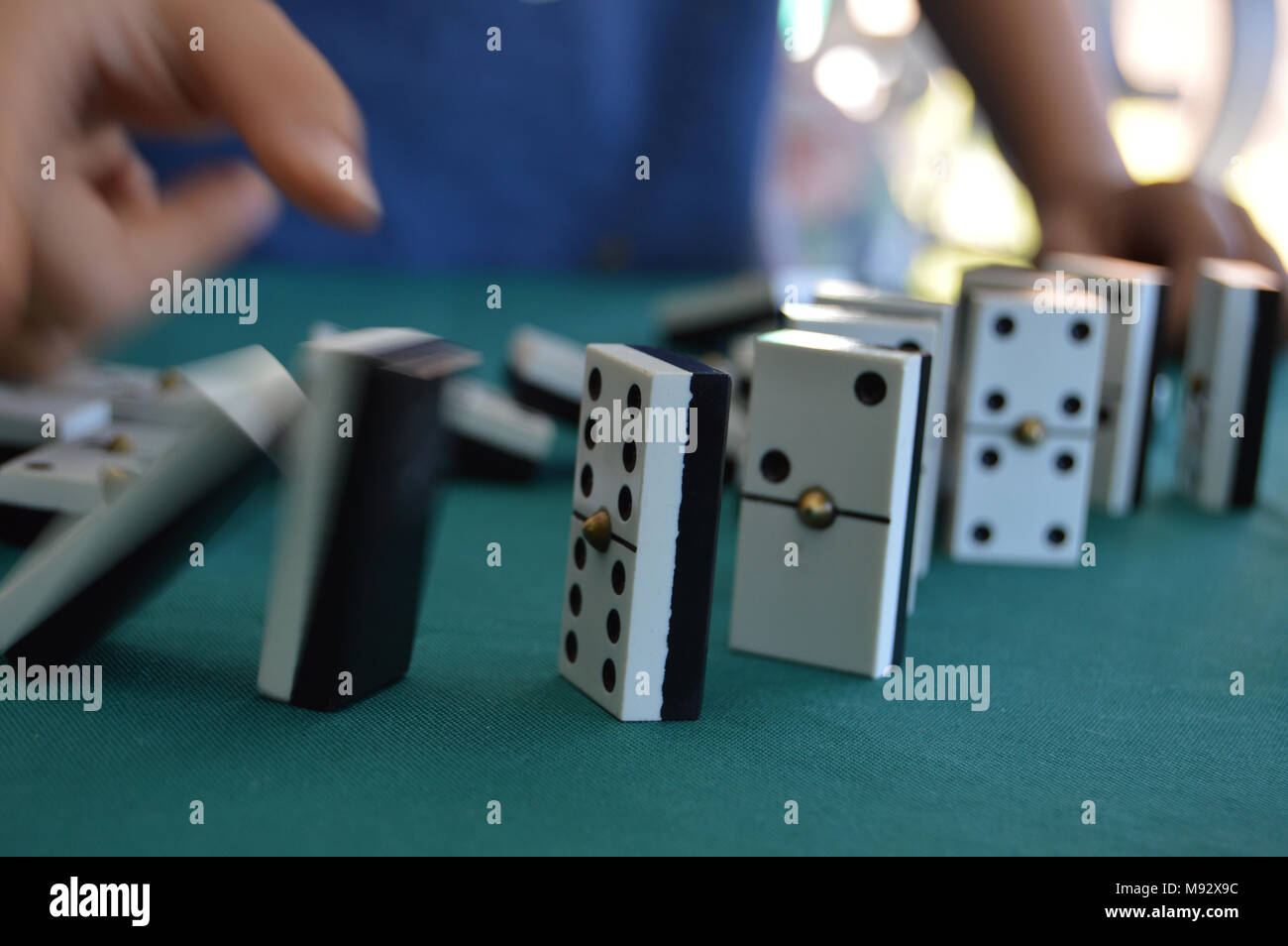 a hand pushing some dominoes Stock Photo - Alamy