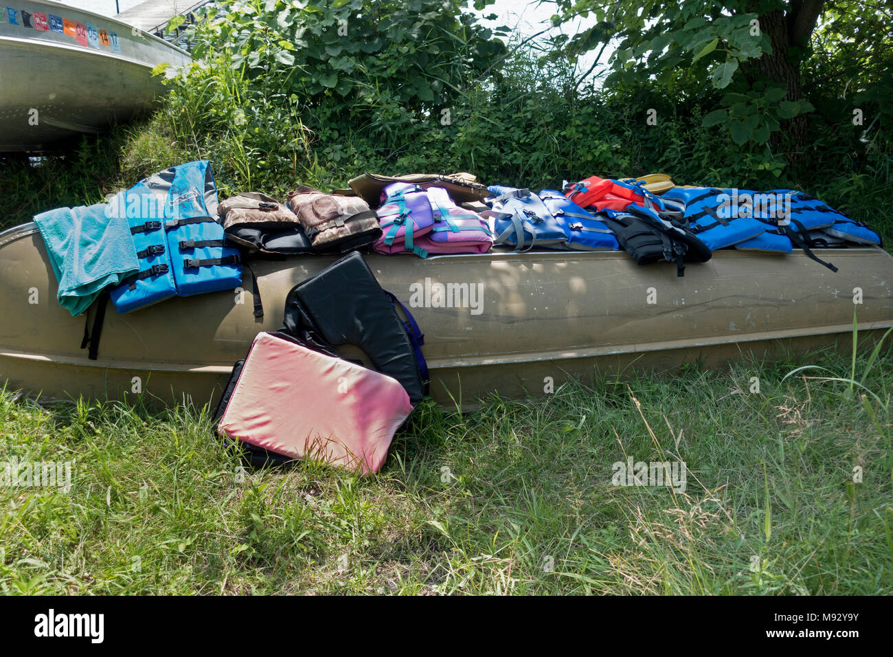 Lineup of life vests and jackets drying on shore on an overturned boat ...