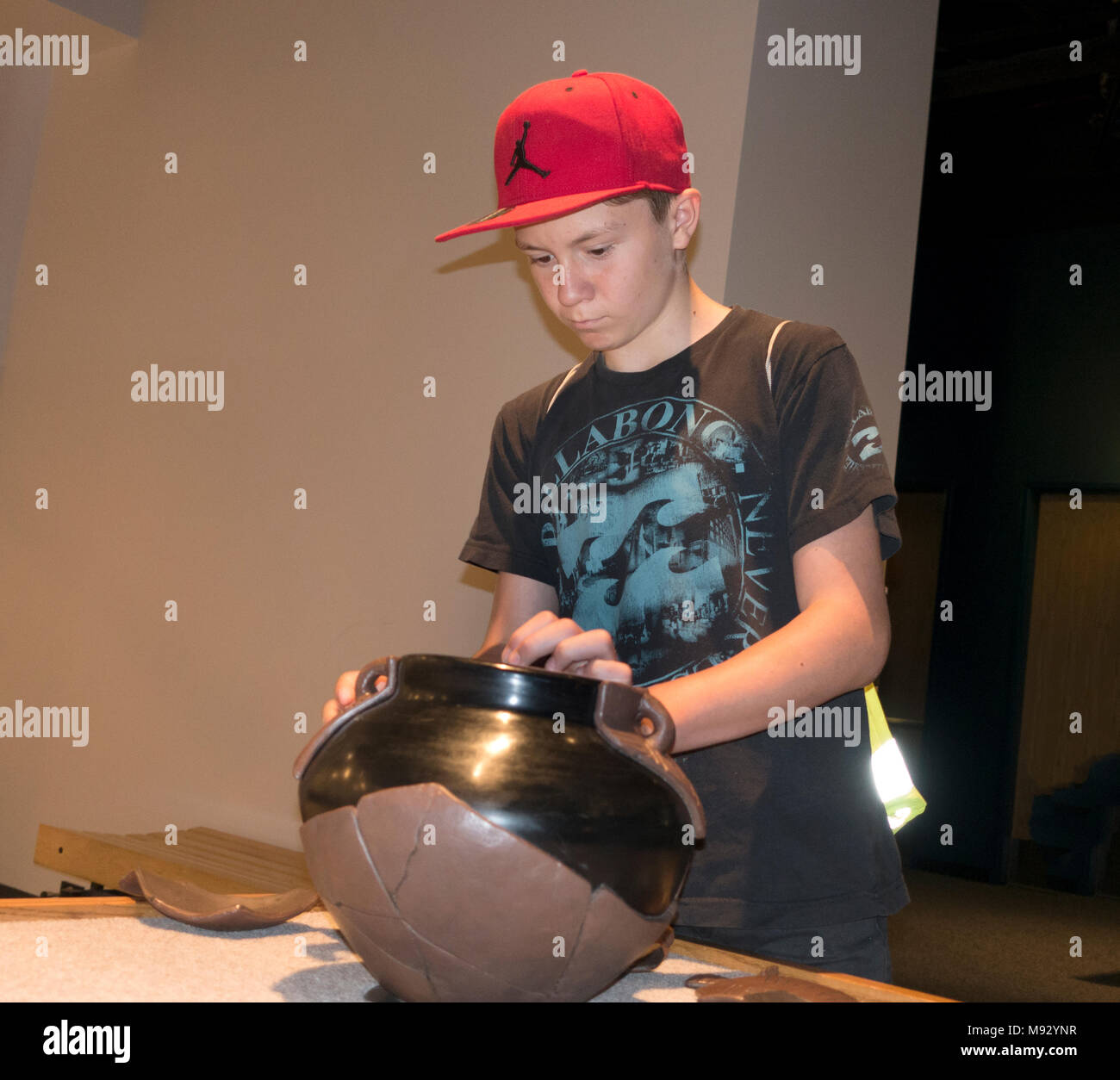 Preteen boy puts pieces of pottery together in an experiment studying ...