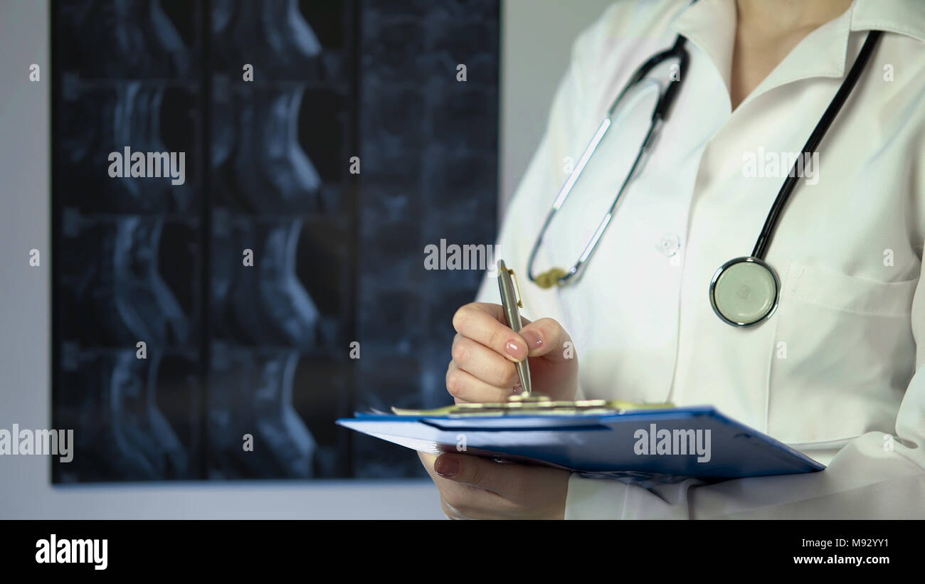 Surgeon writing down patient diagnosis in medical records near X-ray ...