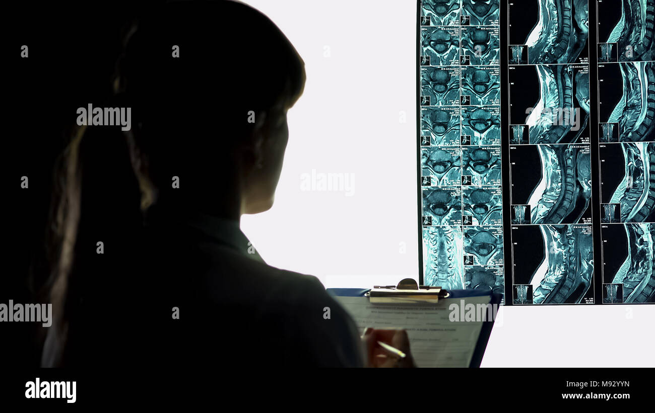 Surgeon analyzing patients X-ray and writing down diagnosis in medical ...