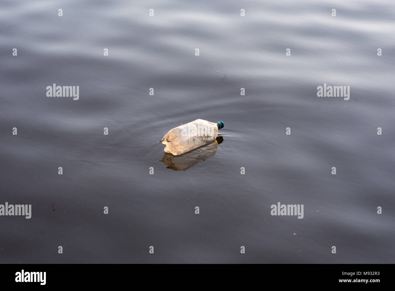 closeup of a single plastic bottle litter floating in body of water ...