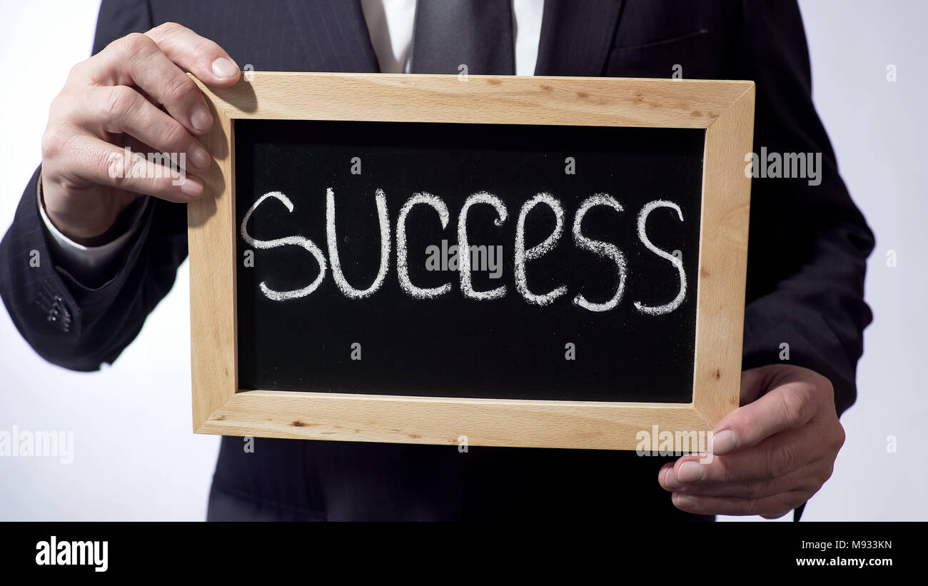 Success written on blackboard, businessman holding sign, business ...