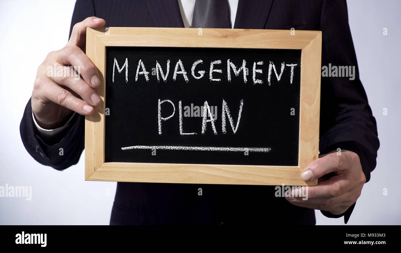 Management plan written on blackboard, business person holding sign ...