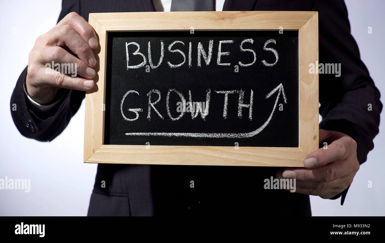 Business growth written on blackboard, male in suit holding sign ...