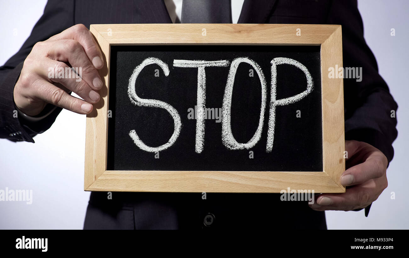 Stop written on blackboard, business person holding sign, motivation ...