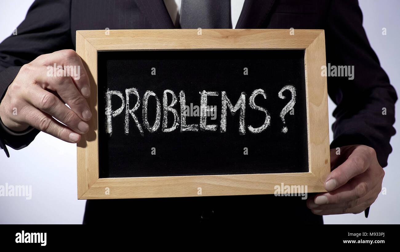 Problems with question mark written on blackboard, businessman holding ...
